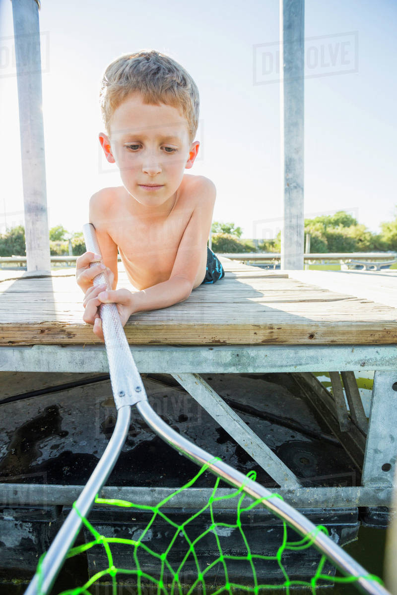 Caucasian boy using fishing net on dock - Royalty-free Stock Photo ...
