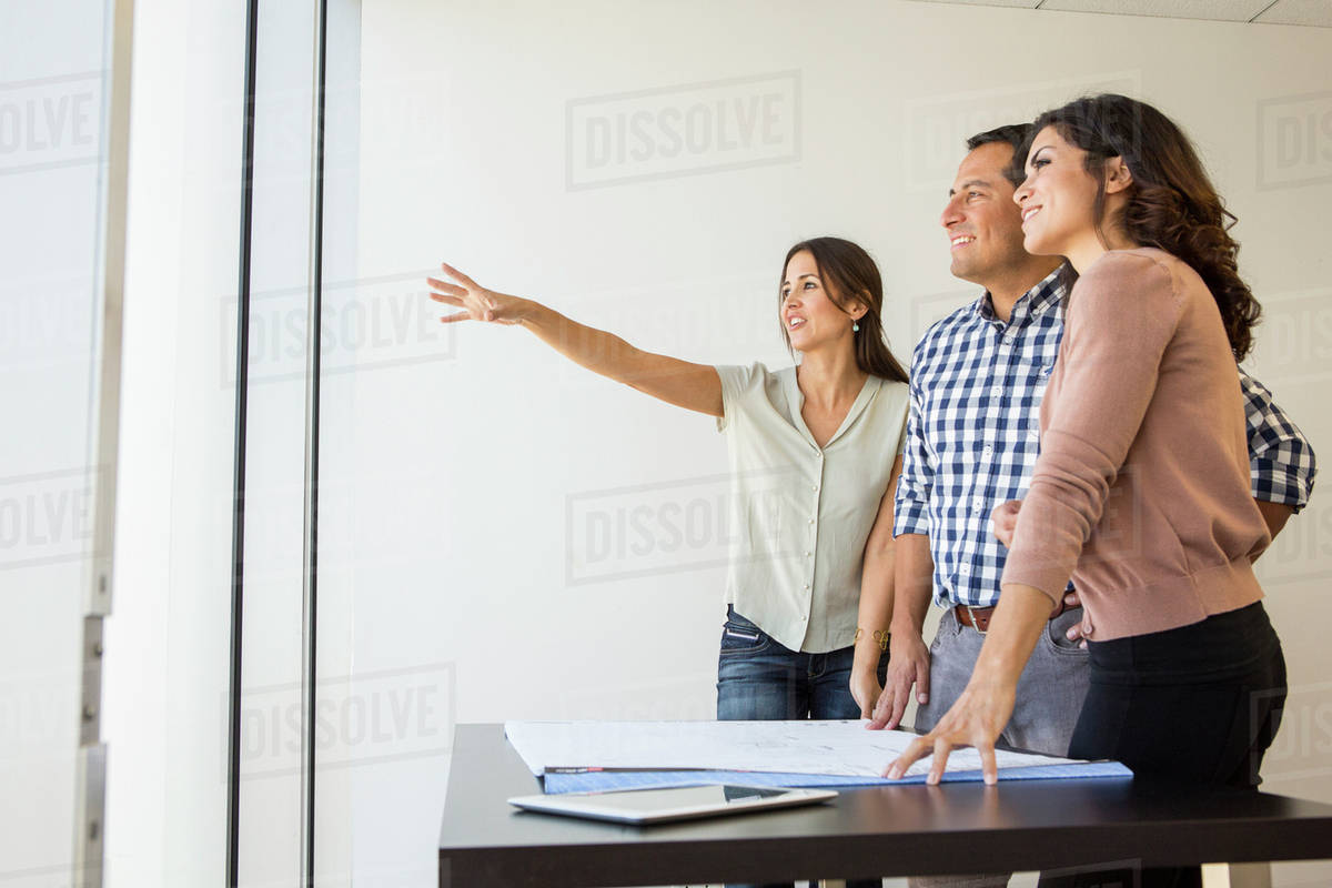 Business people examining blueprints in office - Stock Photo - Dissolve