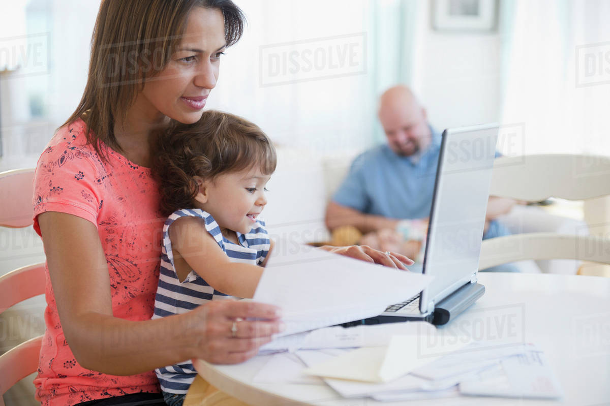 Mother working at computer with child on her lap - Stock Photo - Dissolve