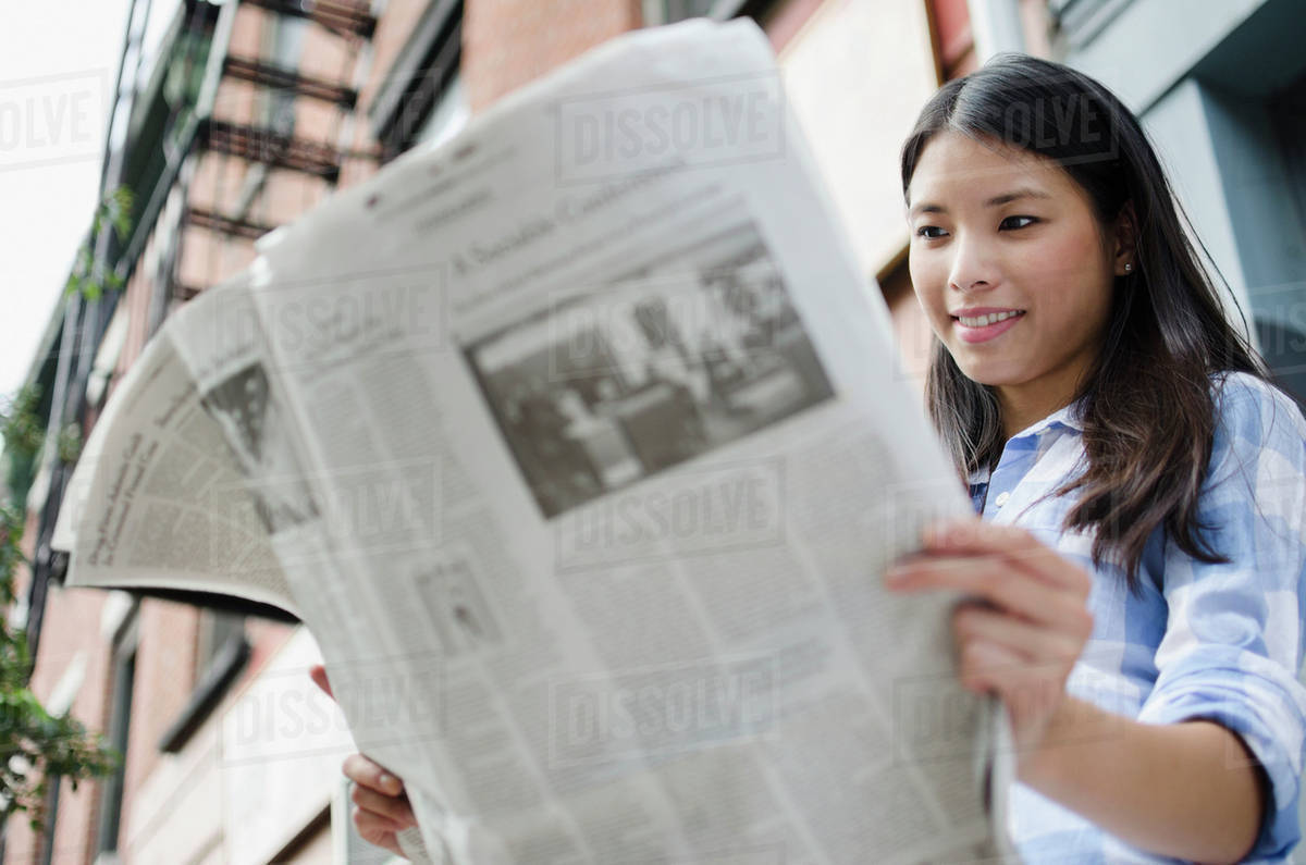 Asian woman reading newspaper - Royalty-free Stock Photo | Dissolve