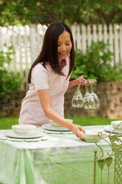 Asian woman setting table outdoors - Royalty-free Stock Photo | Dissolve