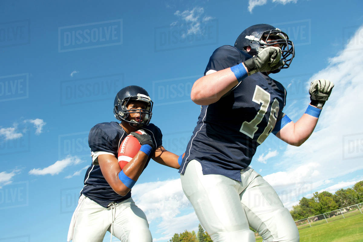 Football players passing ball - Stock Photo - Dissolve