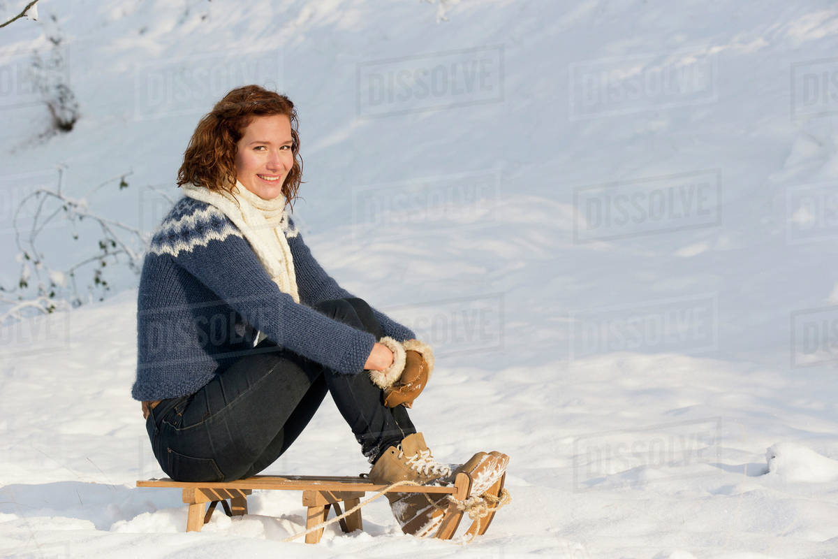 Caucasian woman sitting on sled in snow - Royalty-free Stock Photo ...