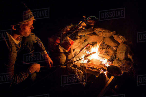 Caucasian man roasting food over campfire - Royalty-free Stock Photo ...