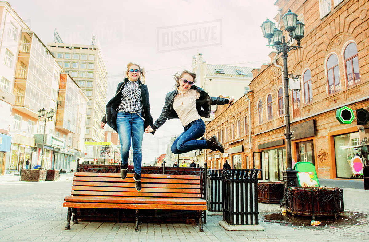 Women jumping for joy near bench - Royalty-free Stock Photo | Dissolve