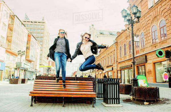 Women jumping for joy near bench - Royalty-free Stock Photo | Dissolve