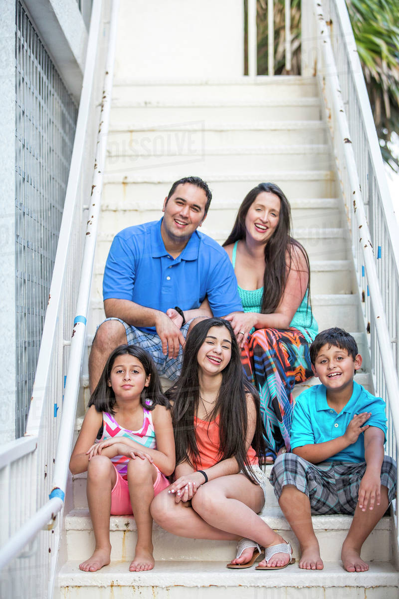 Hispanic family smiling on staircase - Stock Photo - Dissolve