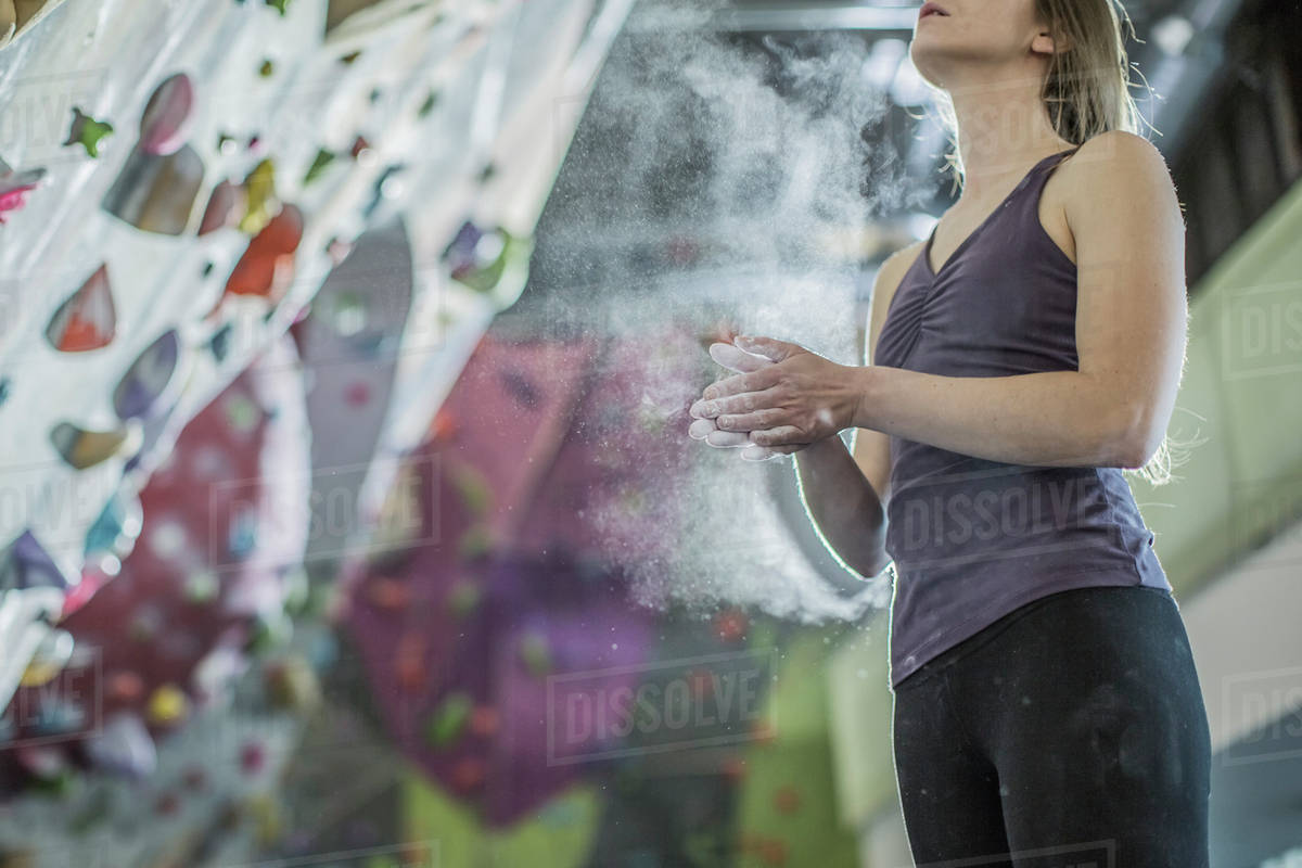 Athlete chalking her hands at rock wall in gym - Royalty-free Stock ...