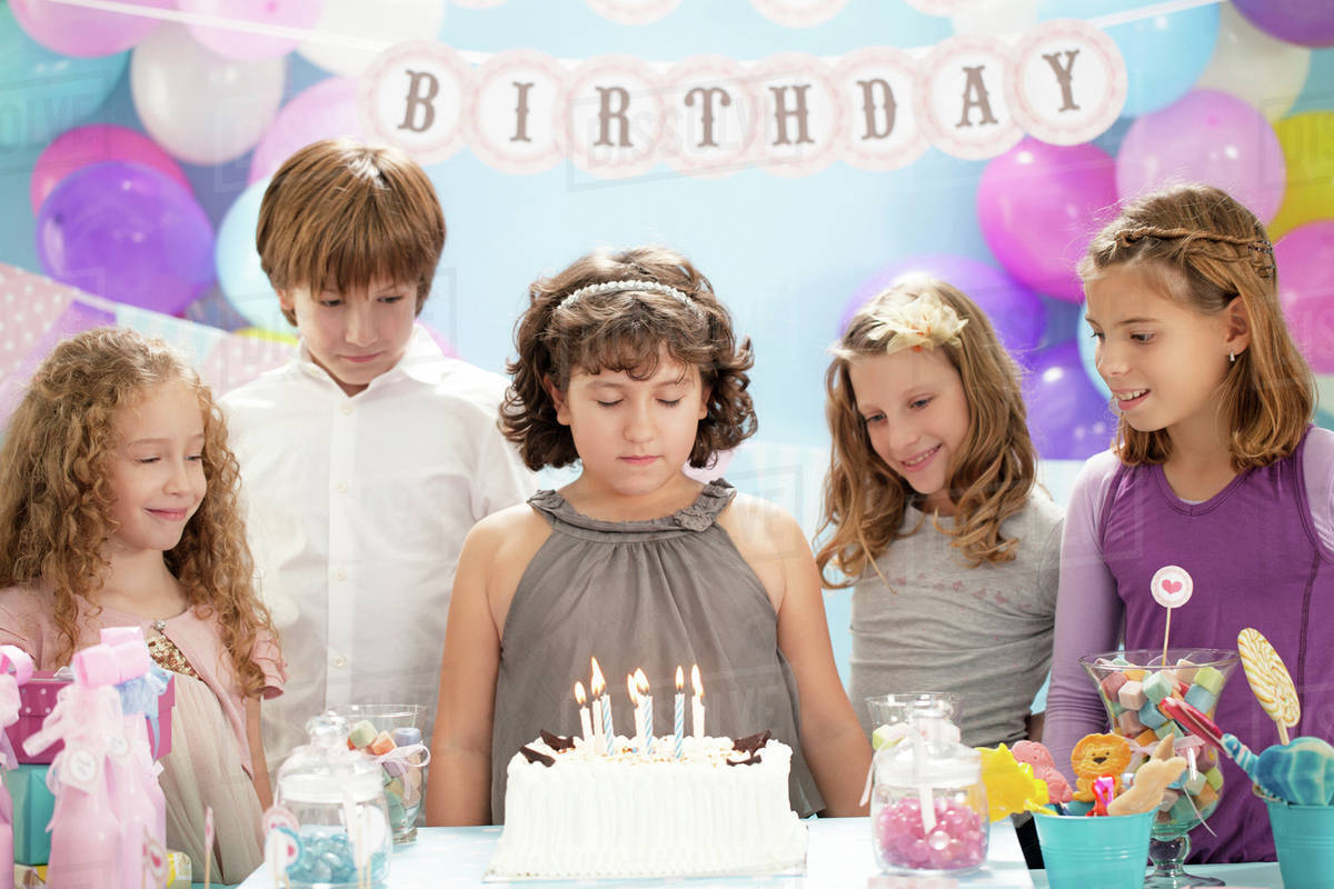 Girl wishing over birthday cake at party - Royalty-free Stock Photo ...