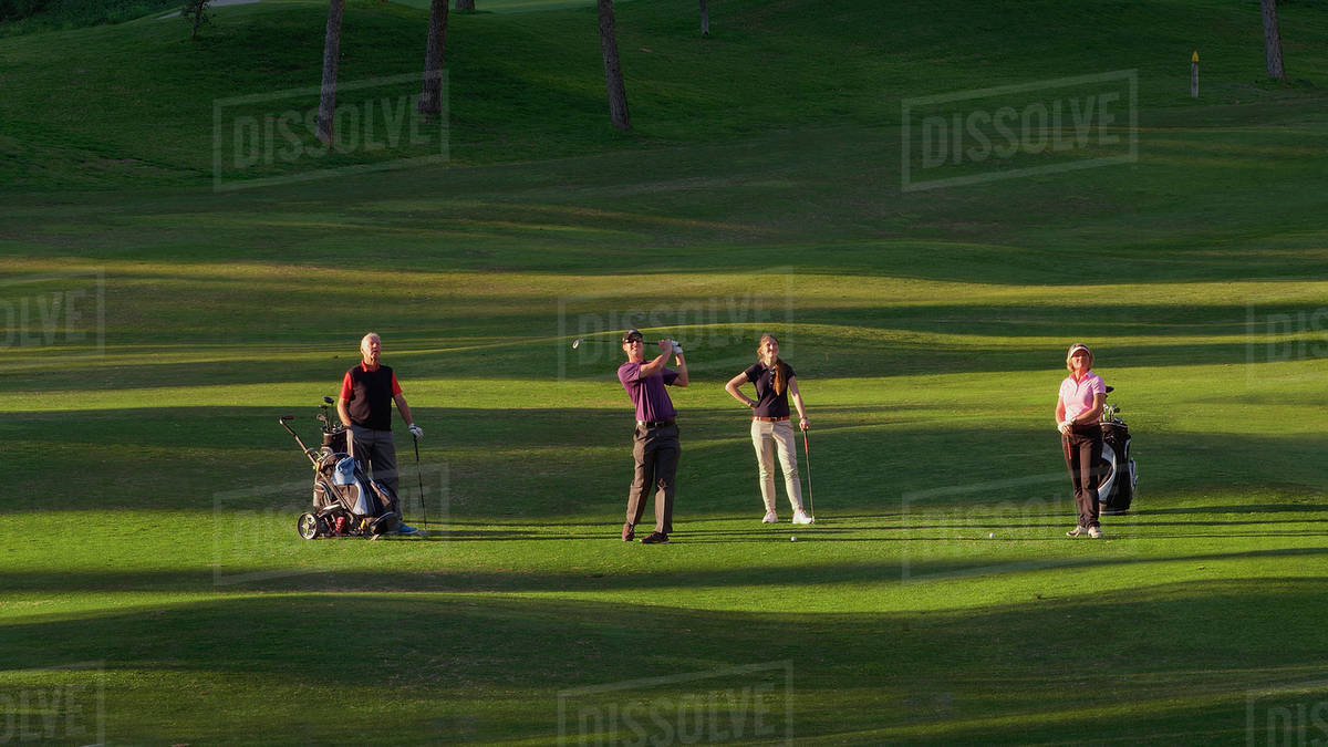 Caucasian friends playing golf on course - Stock Photo - Dissolve