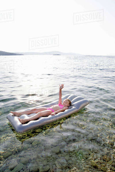 Caucasian girl floating on raft in lake - Stock Photo - Dissolve