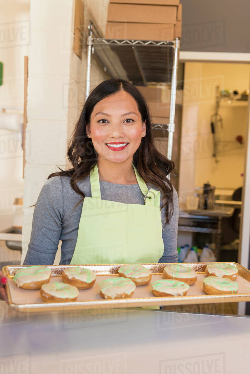 Asian baker holding tray of donuts in bakery - Royalty-free Stock Photo ...