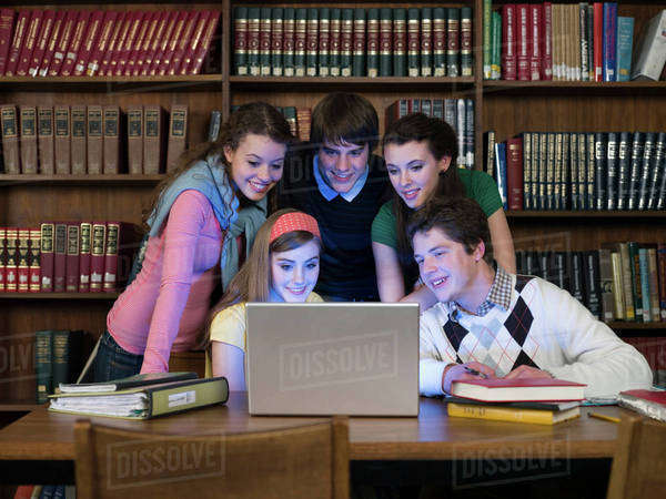 Students using laptop in library - Stock Photo - Dissolve