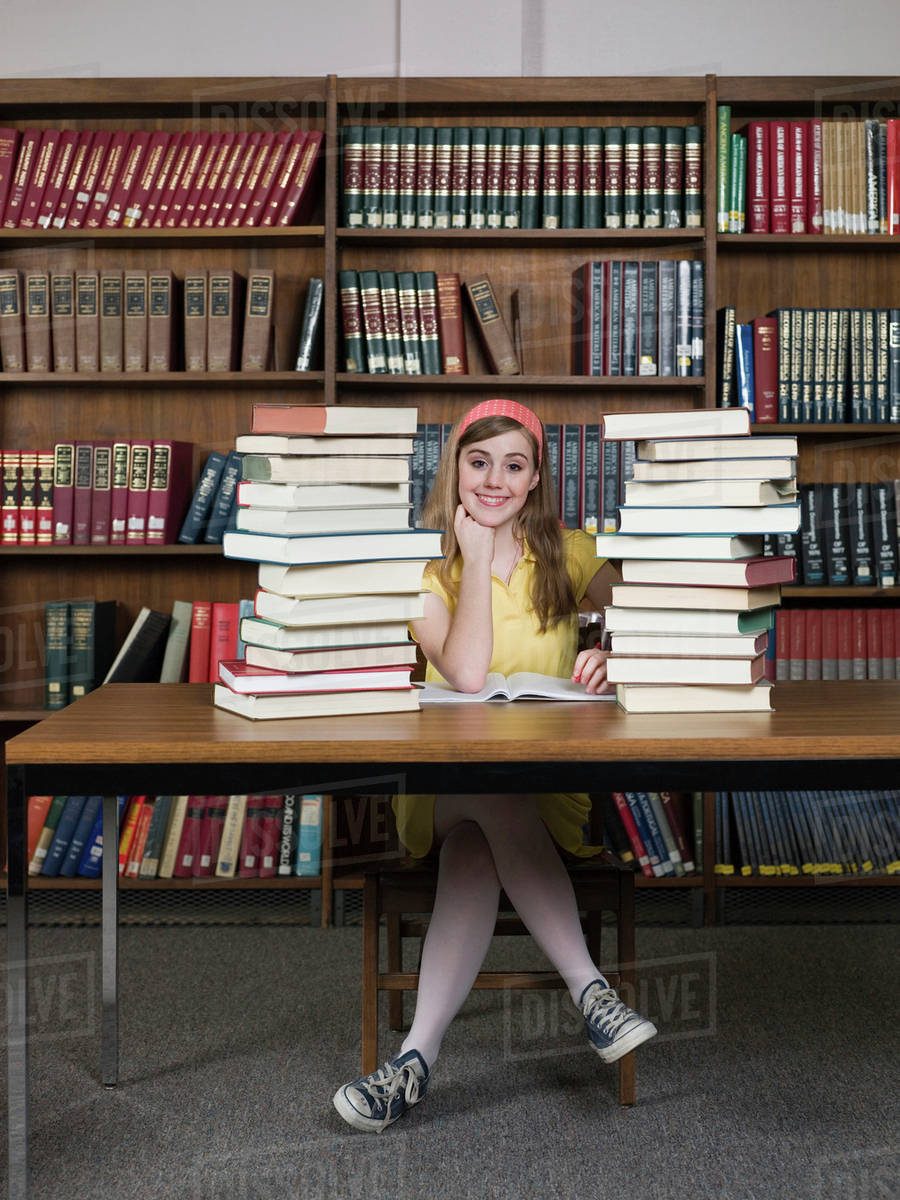 Student sitting with books in library - Royalty-free Stock Photo | Dissolve
