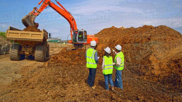 Workers watching digger machinery in field - Stock Photo - Dissolve