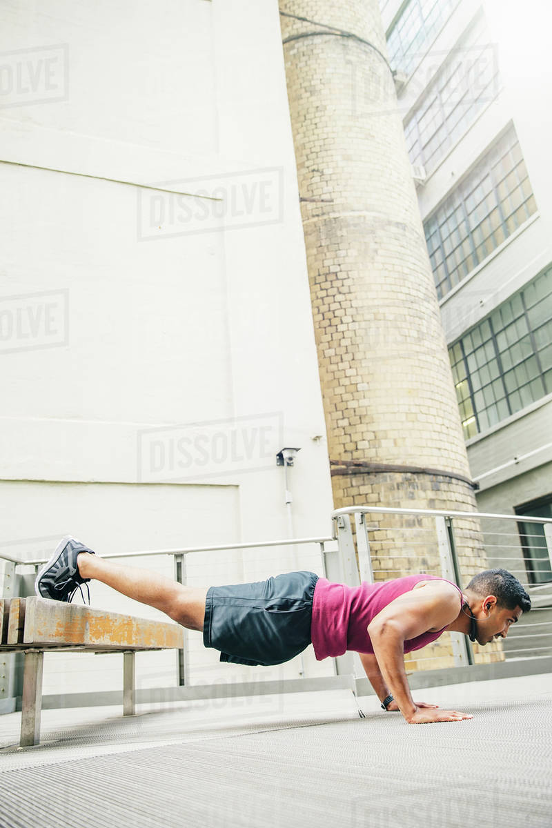 Indian man doing push-ups on bench - Royalty-free Stock Photo | Dissolve
