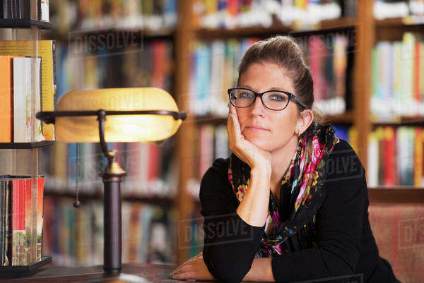 Librarian sitting at desk in library - Stock Photo - Dissolve