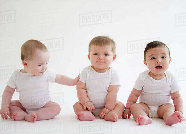 Three babies sitting on floor - Royalty-free Stock Photo | Dissolve