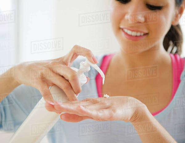 Hispanic woman putting on hand lotion - Royalty-free Stock Photo | Dissolve