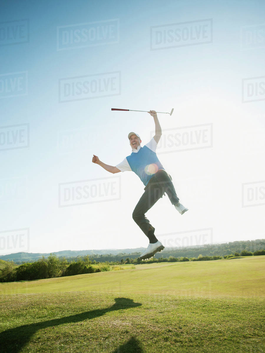 Excited Caucasian golfer jumping in mid-air on golf course - Royalty ...