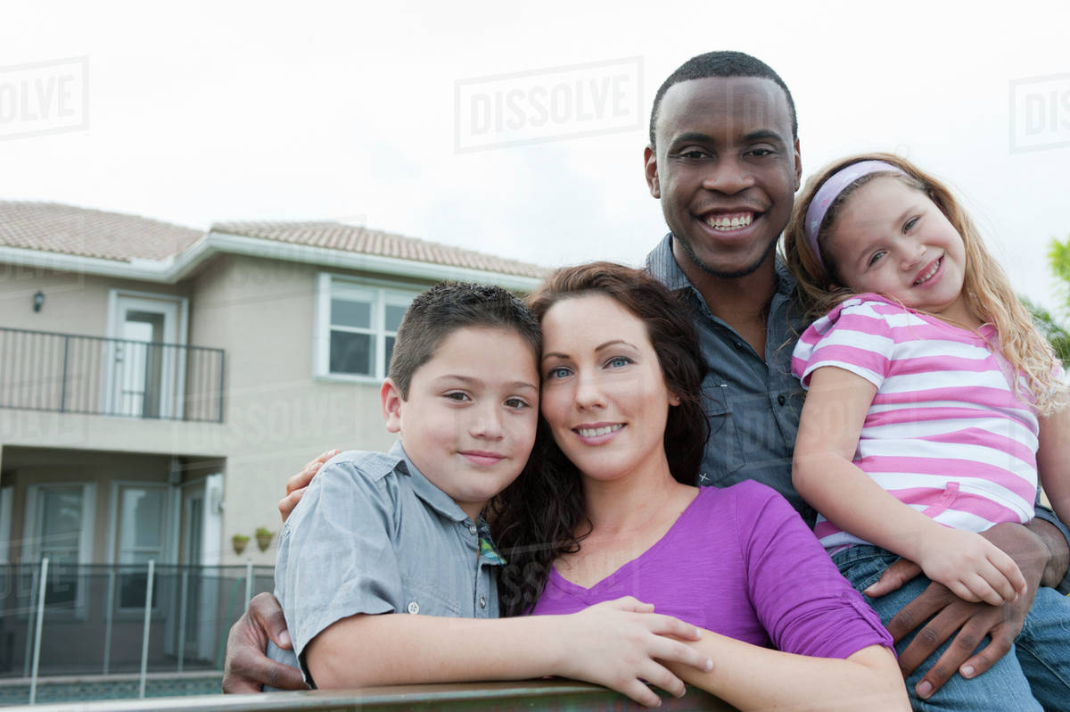 Smiling family hugging outdoors - Stock Photo - Dissolve