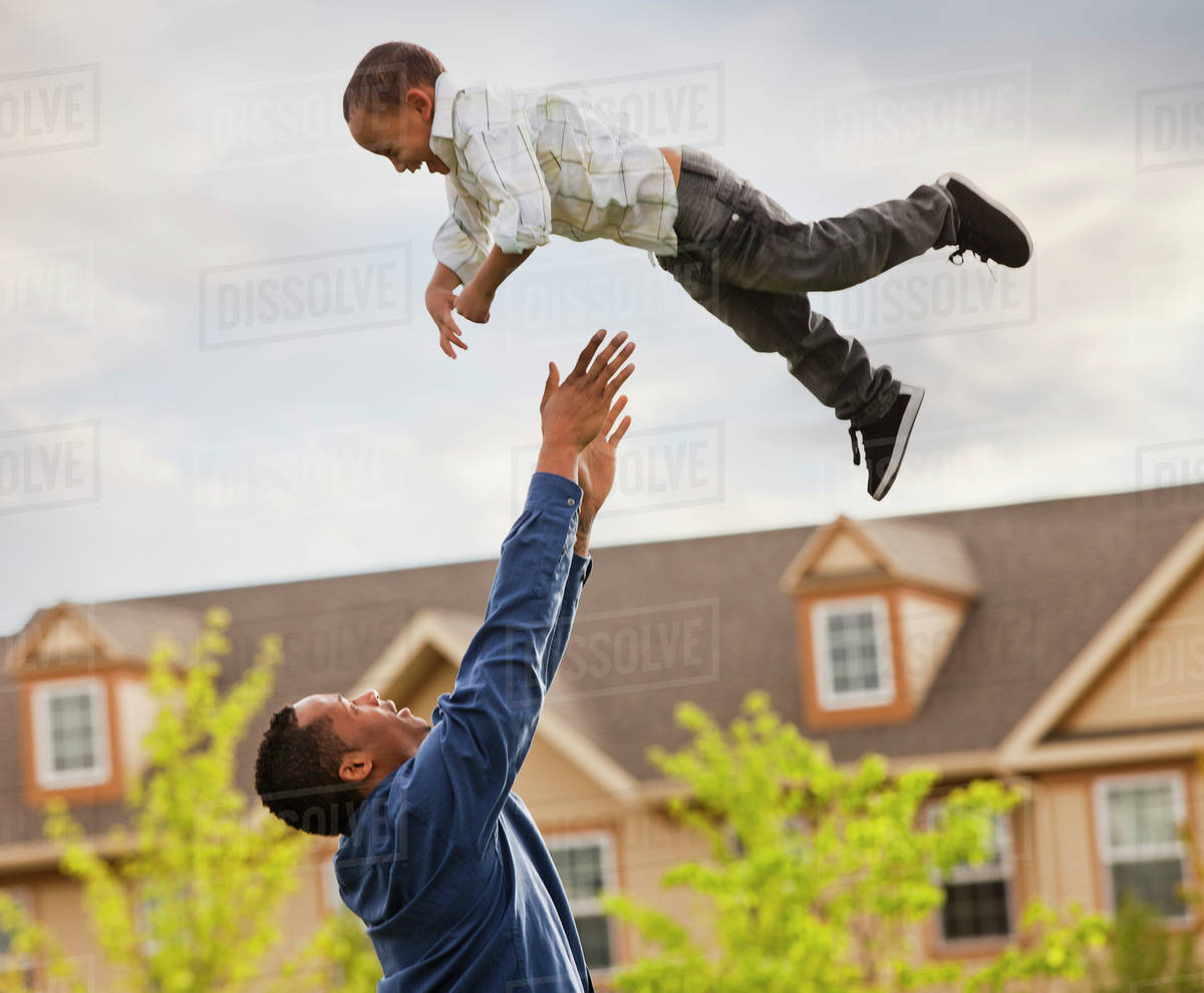 Father throwing son into the air - Stock Photo - Dissolve