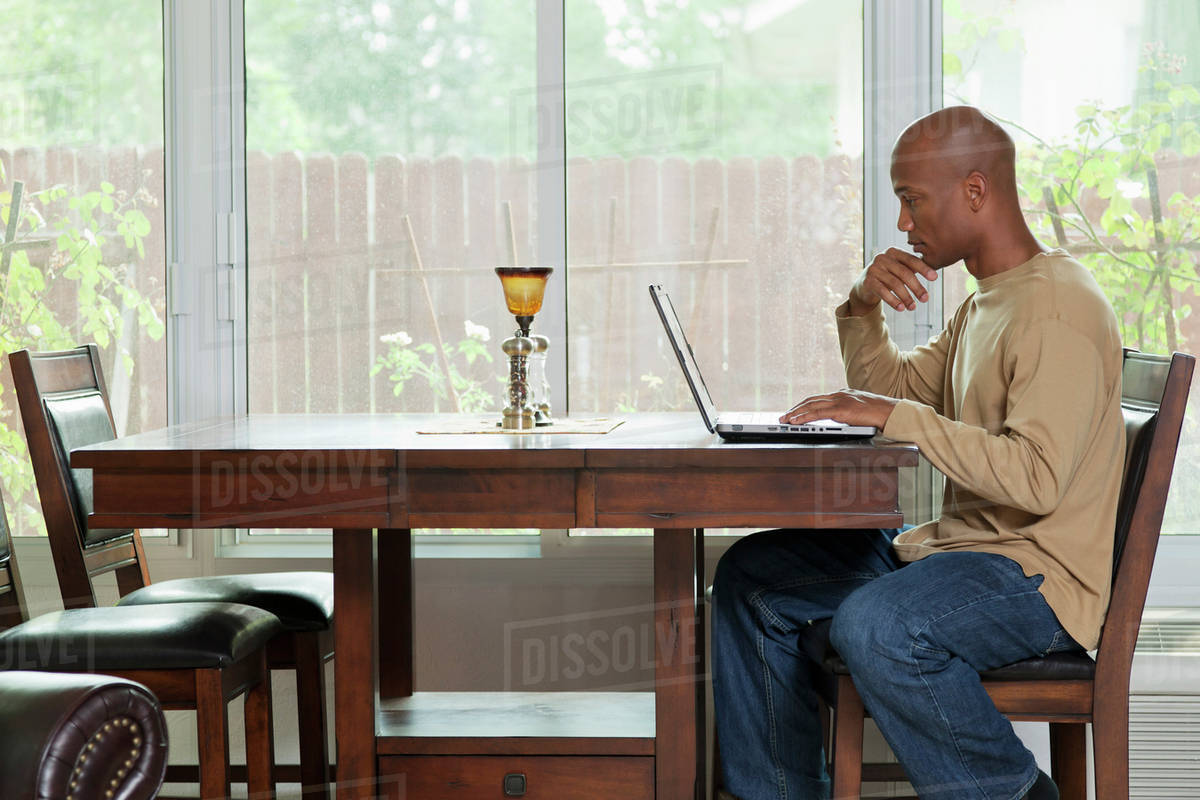 Black man using laptop at table - Stock Photo - Dissolve