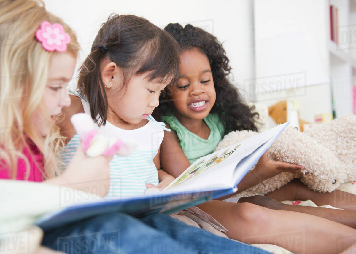 Girls reading book together - Royalty-free Stock Photo | Dissolve
