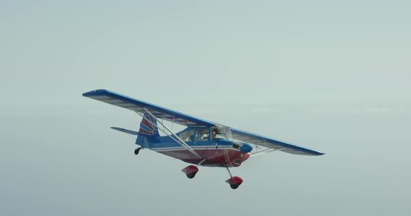 Helicopter aerial of small seaplane flying slightly tilted over ocean ...