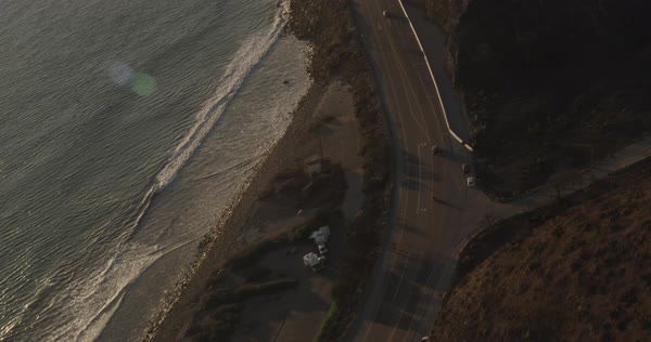 Helicopter aerial birds eye view shot moving down where shore meets PCH ...