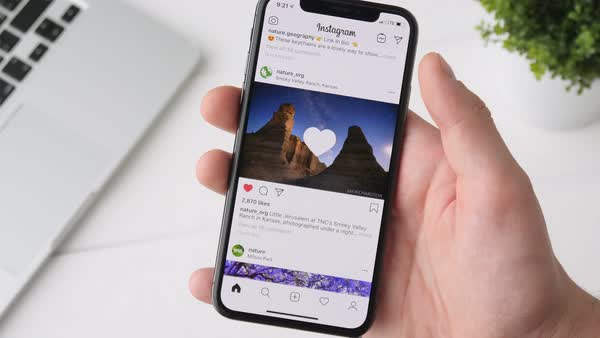 2018: Man using Instagram app on iPhone X smartphone, browsing through ...