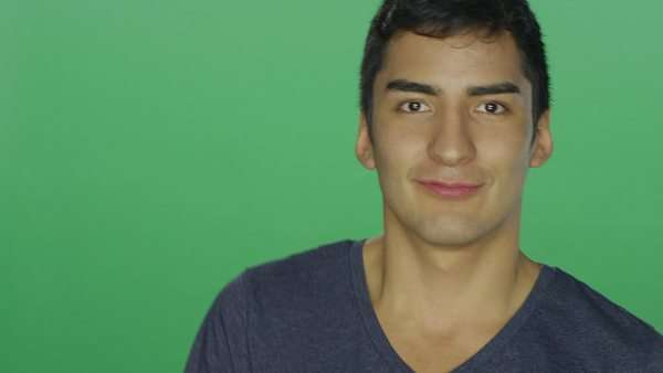 Young man dances and makes funny faces, on a green screen studio ...