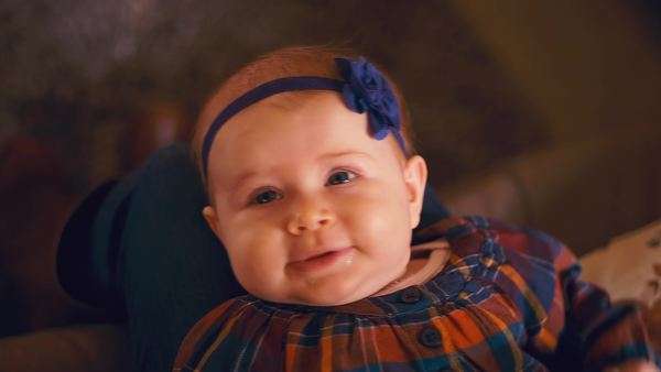 Close-up of a wiggly baby laying on her mother's lap and looking at the ...