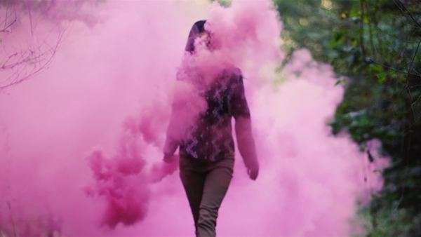 Beautiful young woman in a forest spins around while holding a pink ...