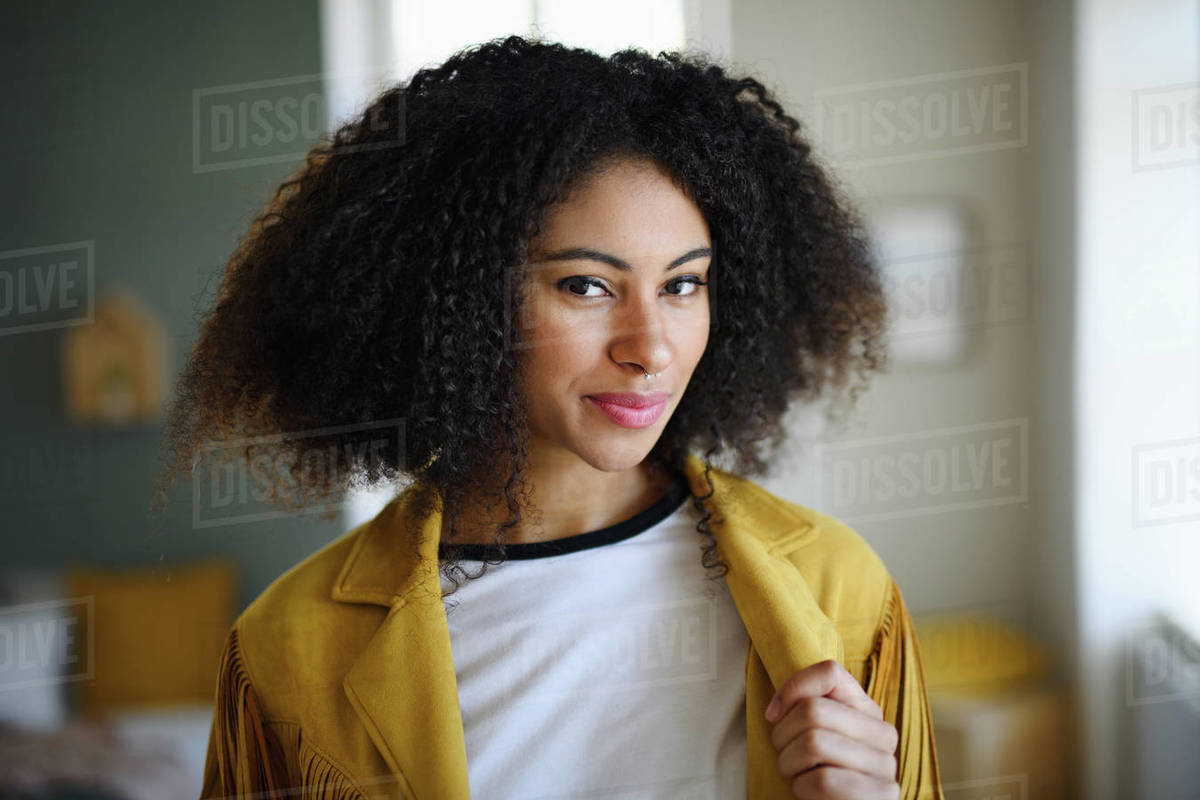 Close-up front view portrait of young woman indoors, looking at camera ...