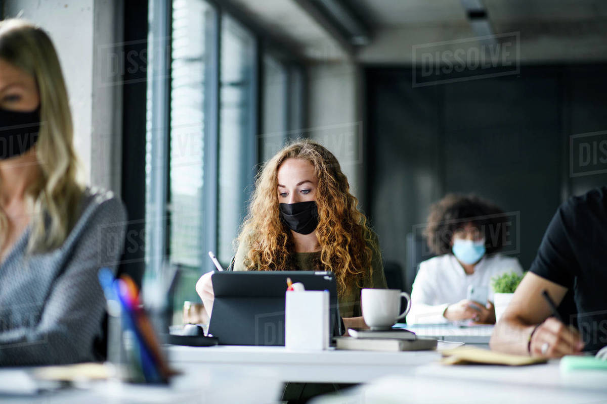 Young people with face masks back at work in office after coronavirus ...