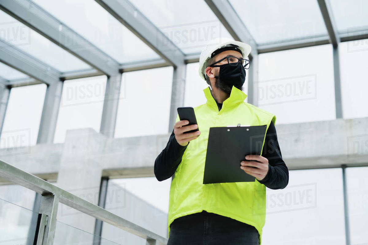 Portrait of worker with face mask, helmet and high visibility vest ...