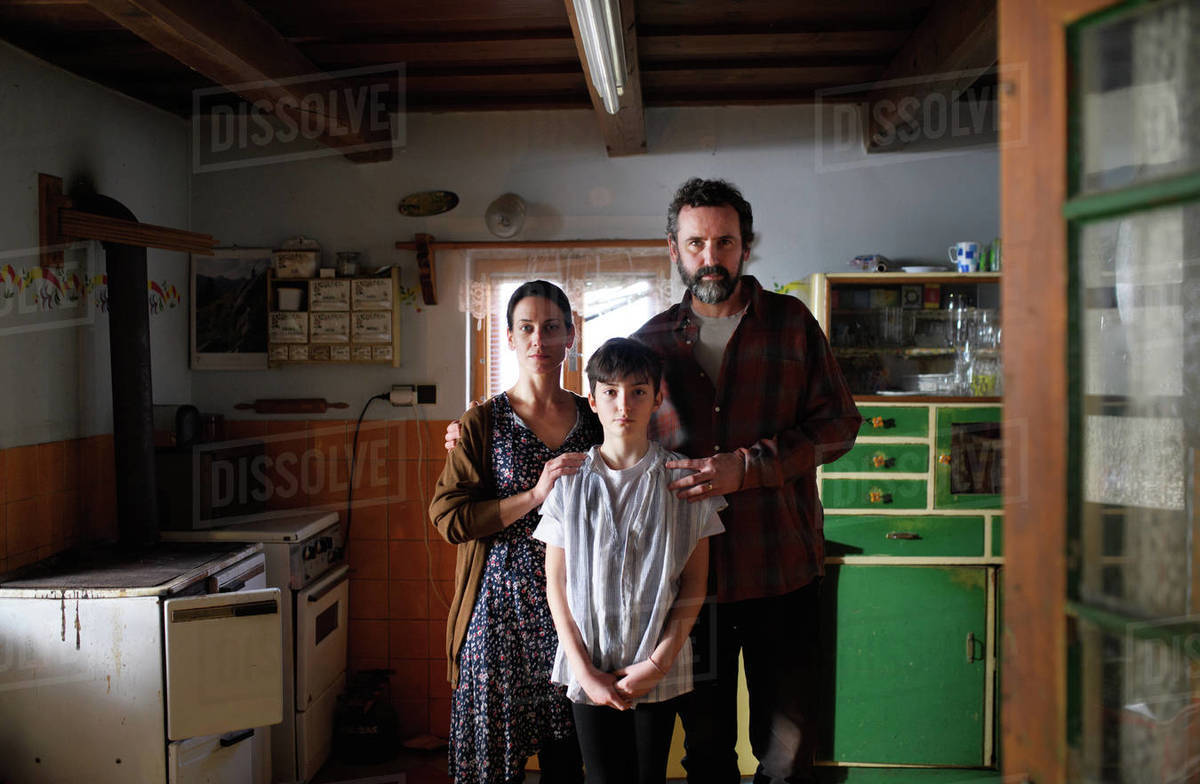 Portrait of poor mature couple with small daughter indoors in kitchen ...