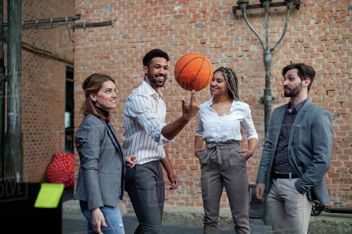 A group of cheerful young businesspeople playing basketball in office ...