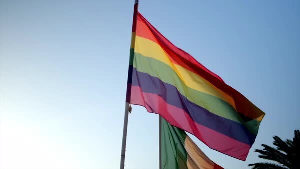 Slow motion pan to right of a beautiful pride flag waving in the wind ...