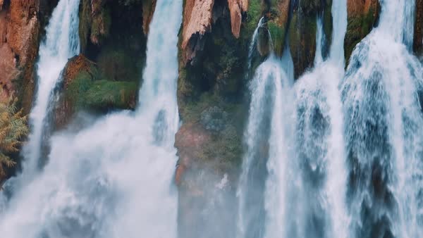 White foamy waterfall flows from the cliff. Close-up drone footage. The ...