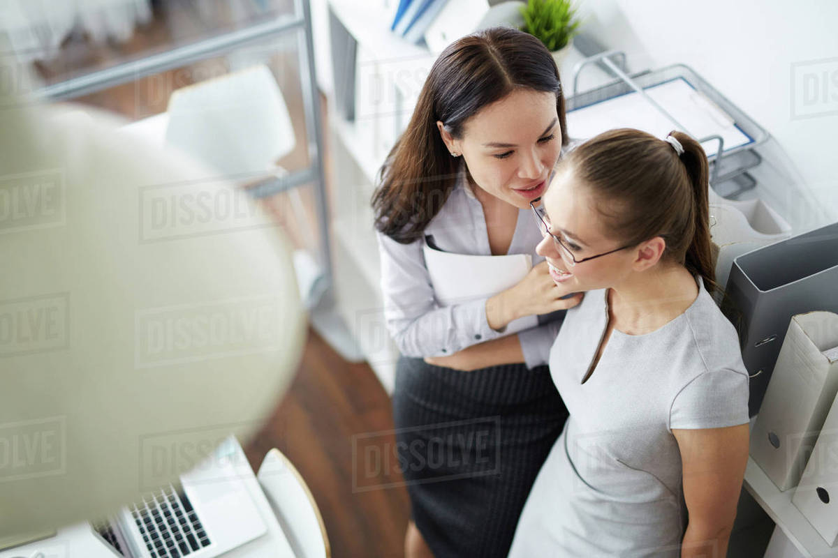 Two young women interacting in office - Royalty-free Stock Photo | Dissolve