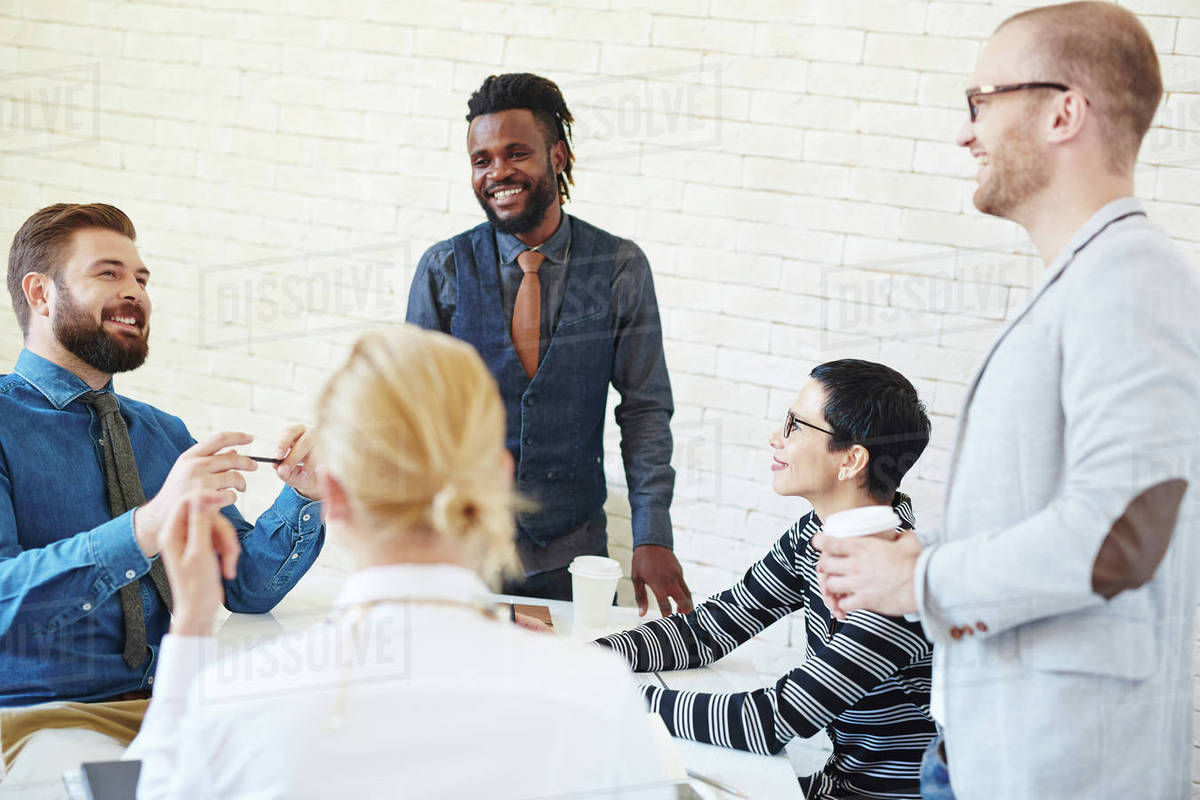 Group of young business men and women meeting in office, talking and ...