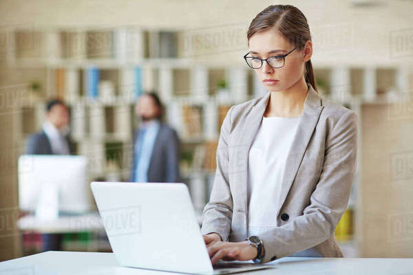 Serious secretary typing on laptop at office - Royalty-free Stock Photo ...