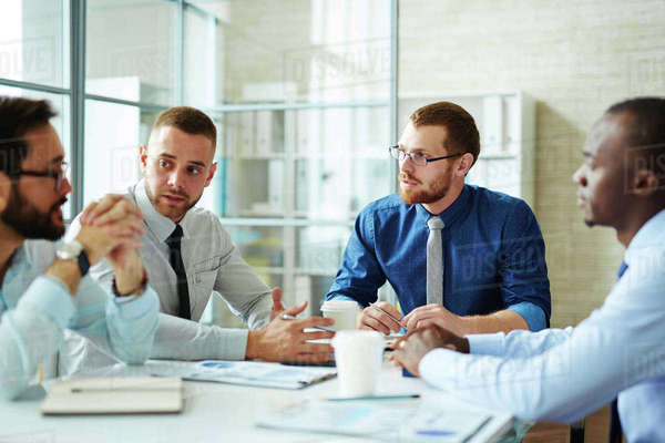 Male employees listening to colleague at briefing - Stock Photo - Dissolve