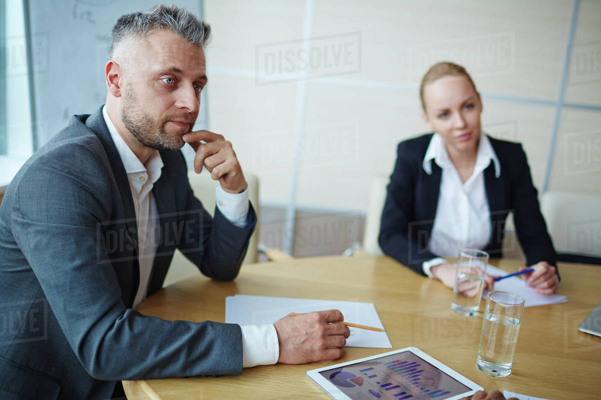 Serious businessman listening to colleague or young specialist at ...
