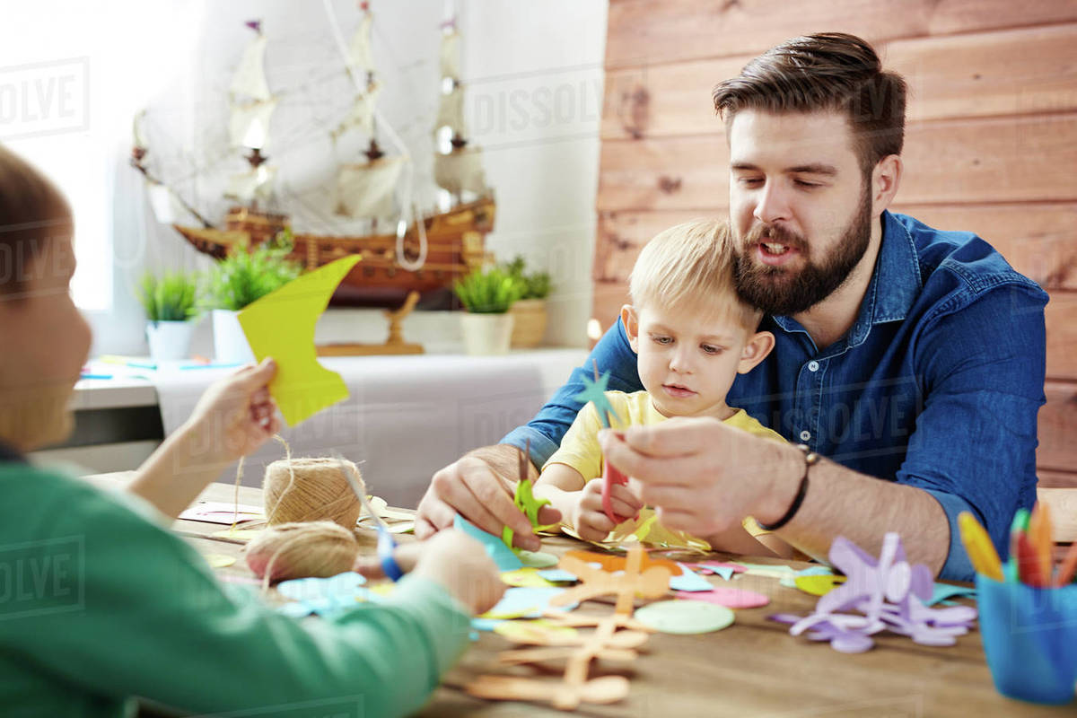 Father and sons cutting out figures from paper - Royalty-free Stock ...