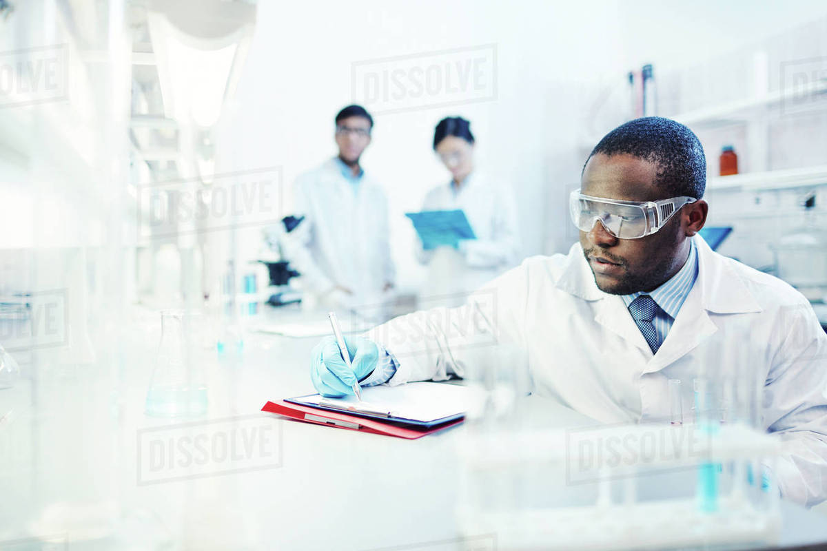 Young scientist taking notes in lab - Stock Photo - Dissolve