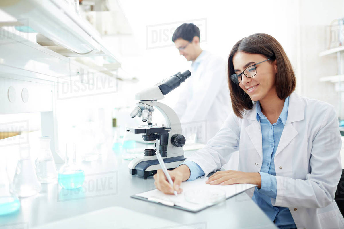 Pretty young scientist taking notes in a laboratory - Royalty-free ...