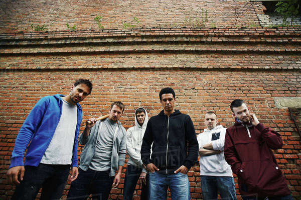 Group of angry young men in hoodies in front of a brick wall - Royalty ...